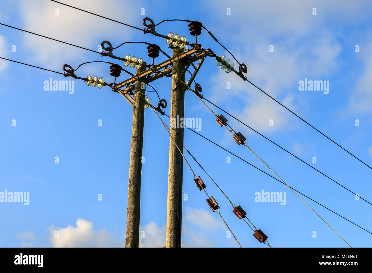 Electrical Power lines fixed to wooden poles with a blue sky background ...
