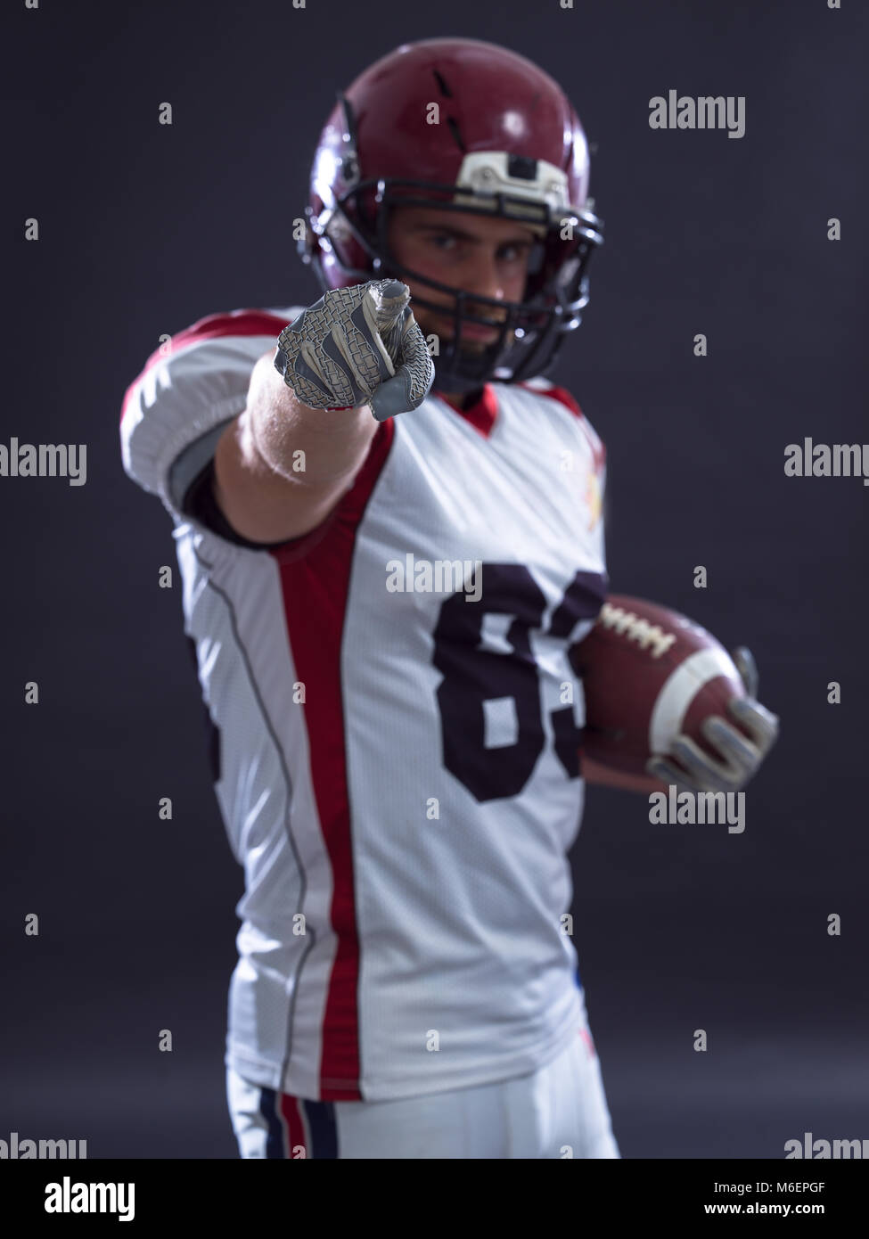 Portrait of American football player pointing against gray background ...