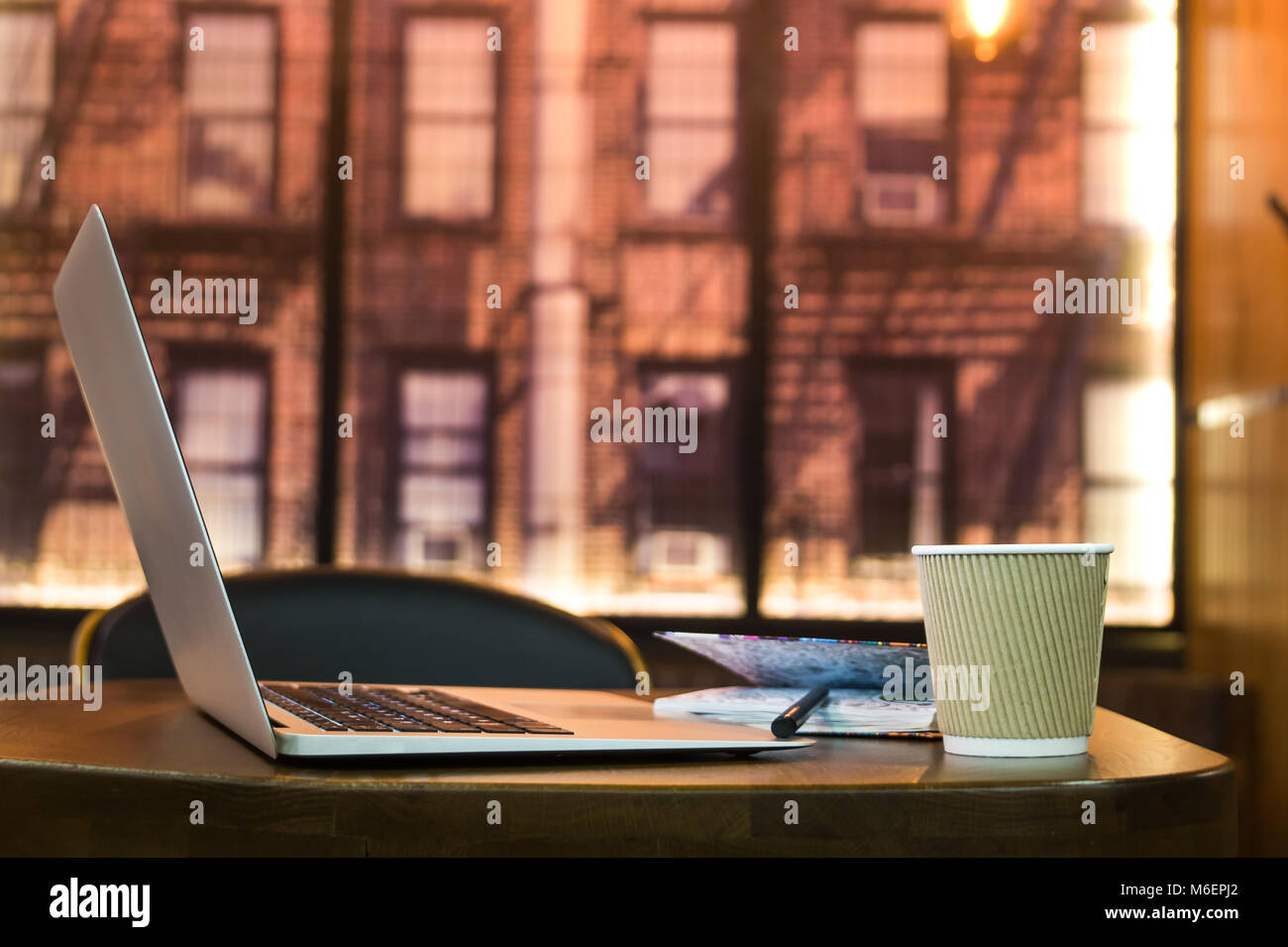 Coffee cup and laptop on the table in cafe. Portable computer, note pad ...