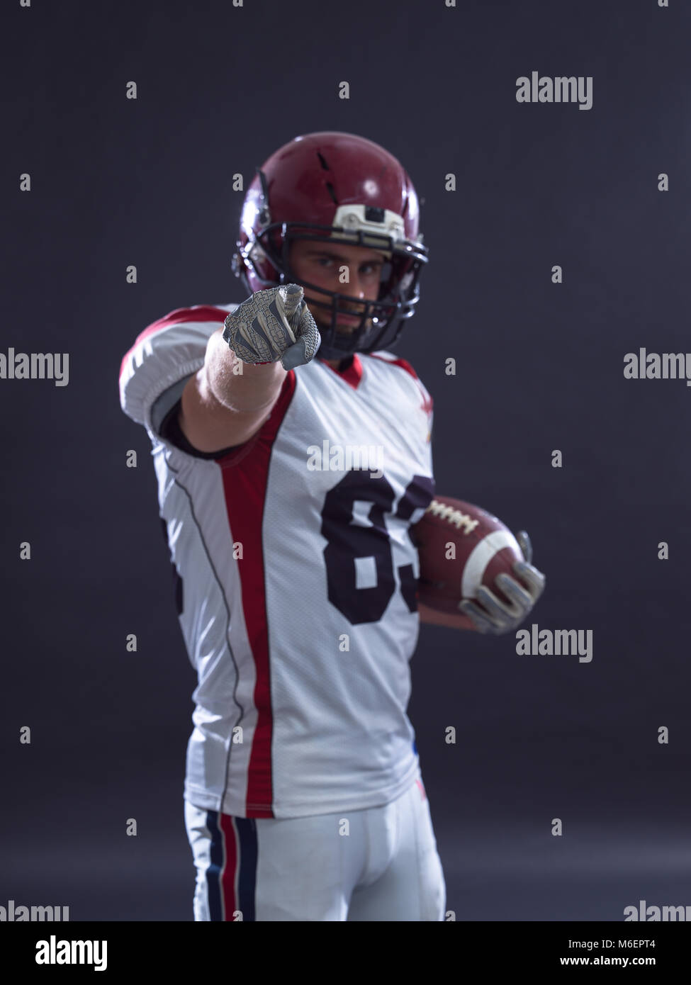 Portrait of American football player pointing against gray background ...
