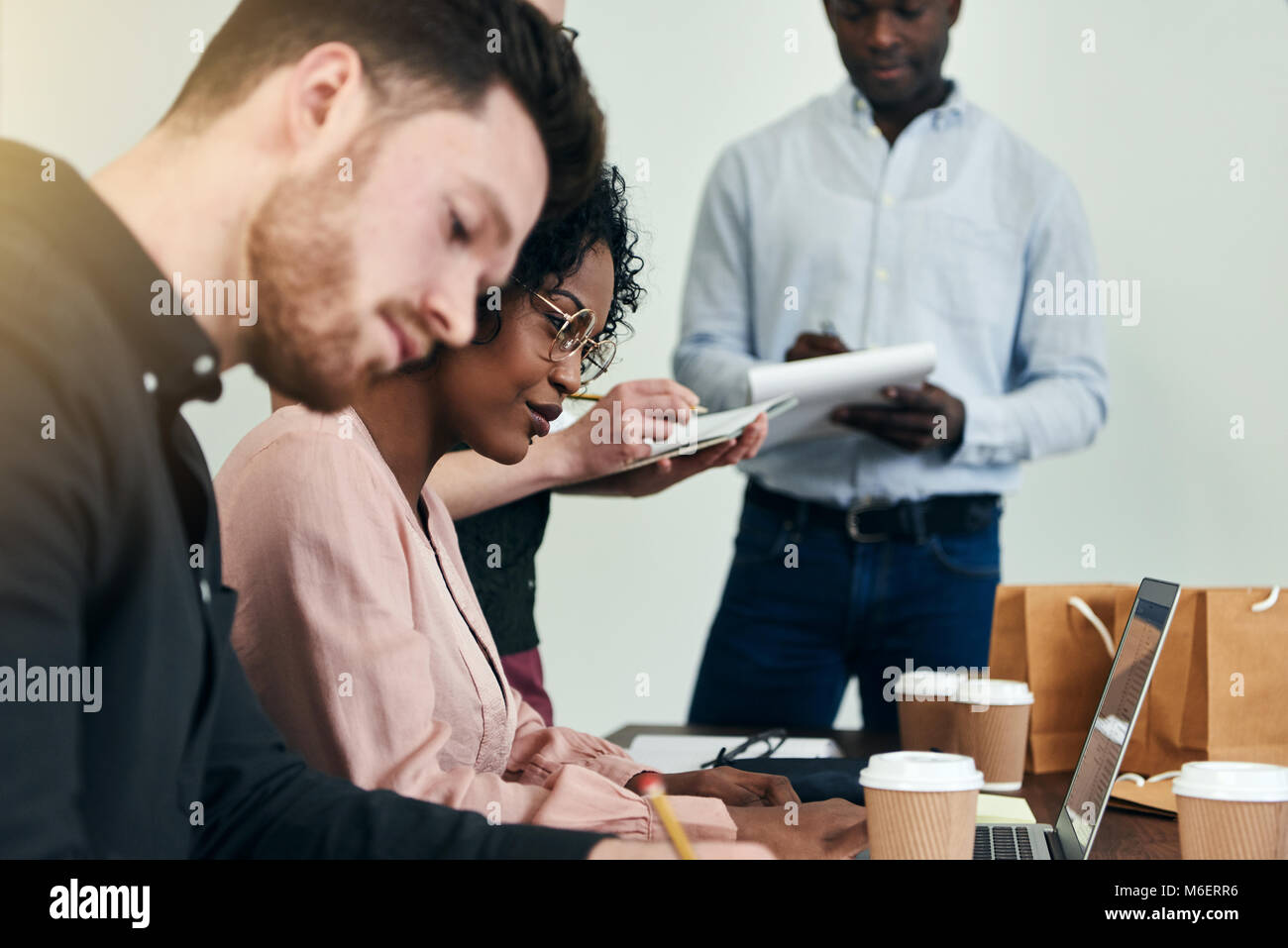 Diverse group of focused businesspeople working together while sitting ... Diverse group of focused businesspeople working together while sitting ...