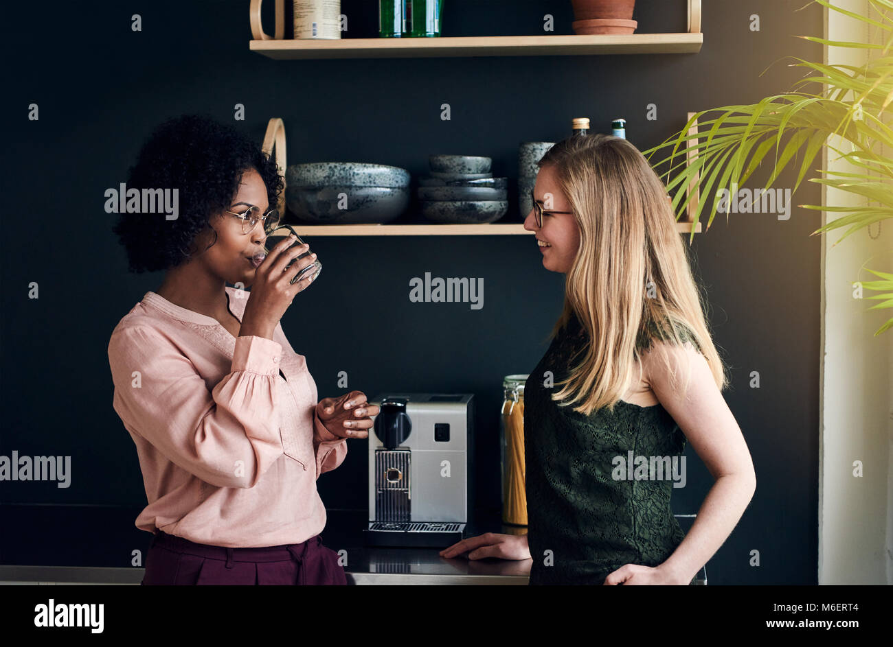 Two diverse female work colleagues smiling and talking together while ...