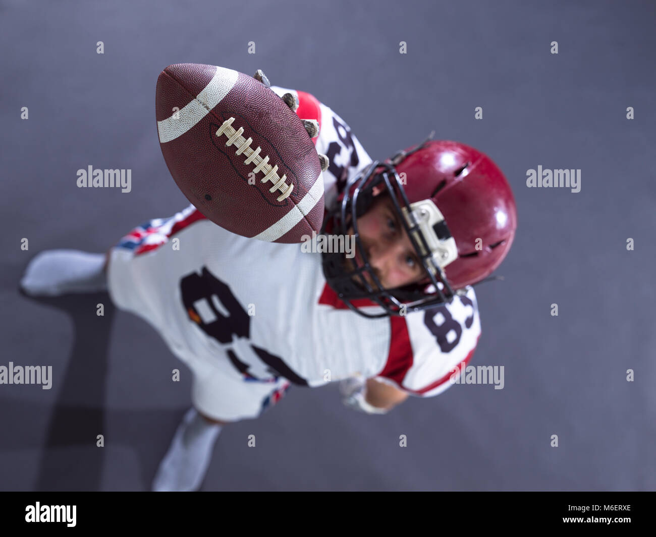 Portrait of american football player showing football to camera against ...