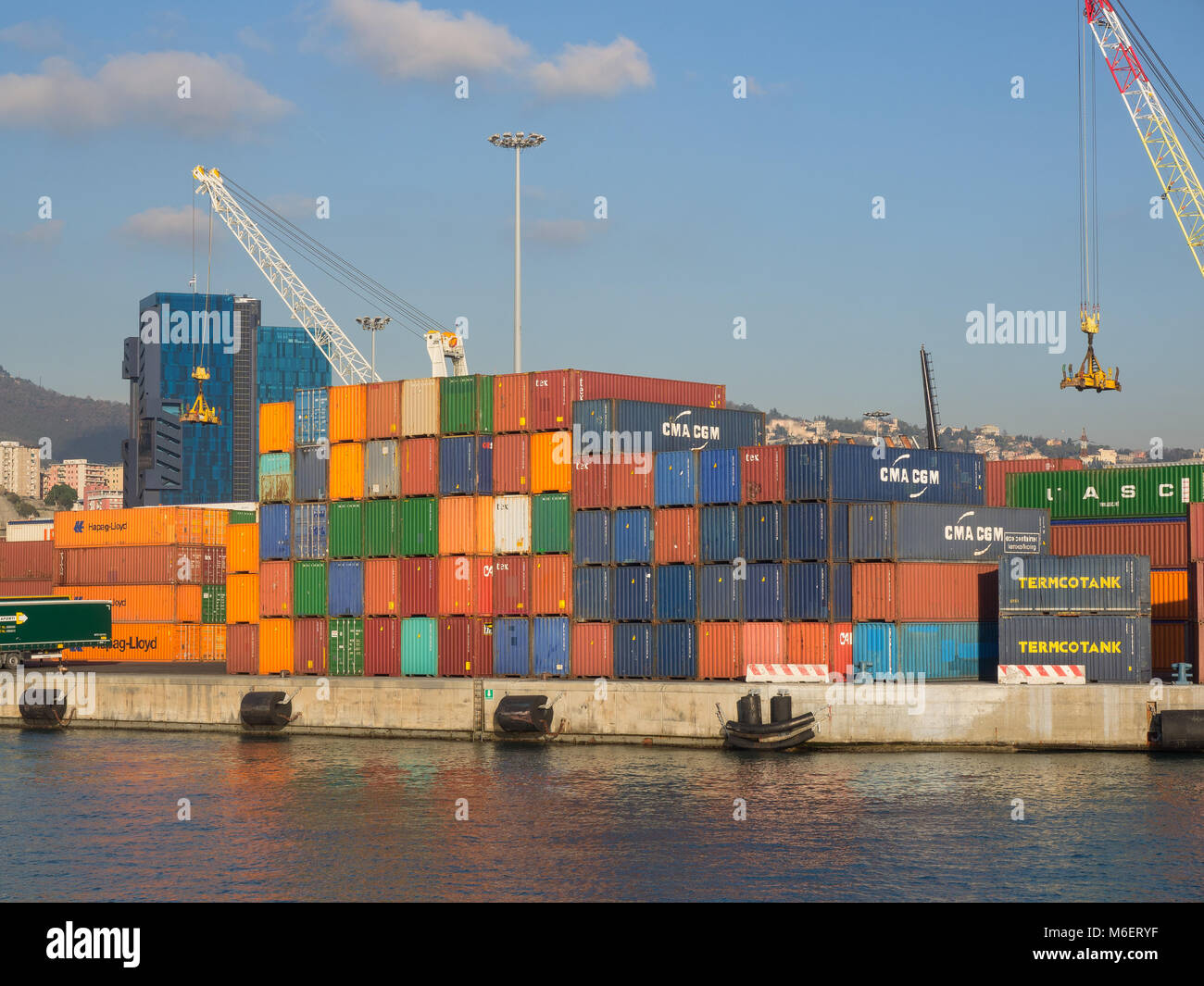 Many colorful containers stacked on a dock reflecting in the water of ...
