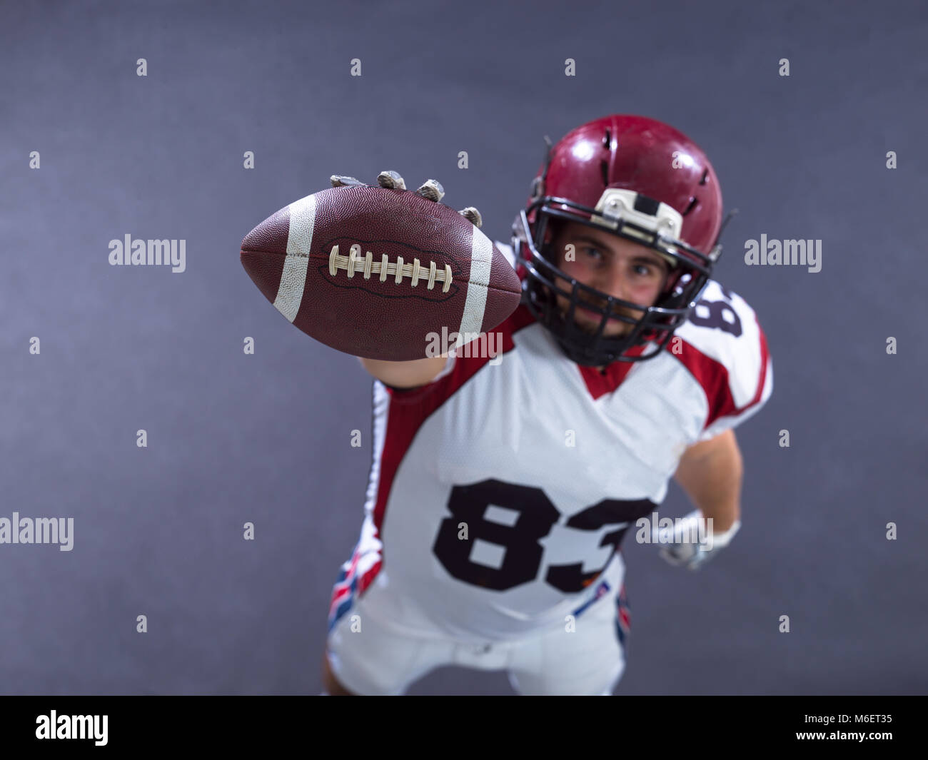 Portrait of american football player showing football to camera against ...
