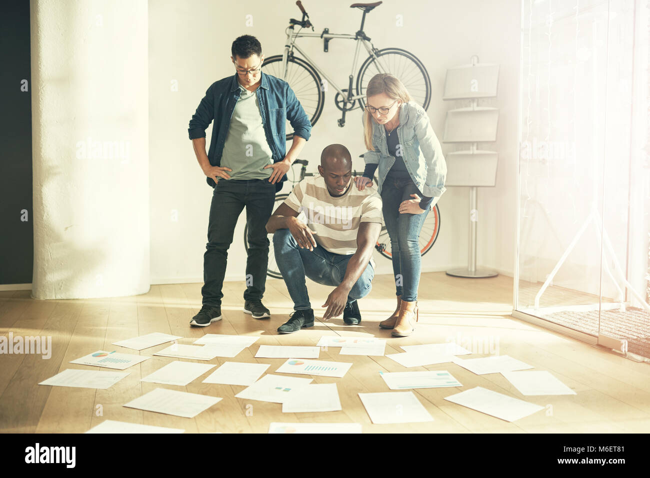 Three diverse work colleagues standing in a stylish modern office ...
