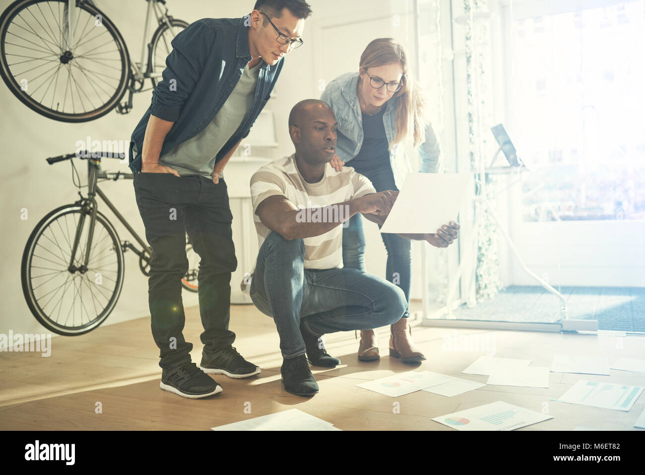 Three diverse colleagues reading a document from paperwork laying out ...