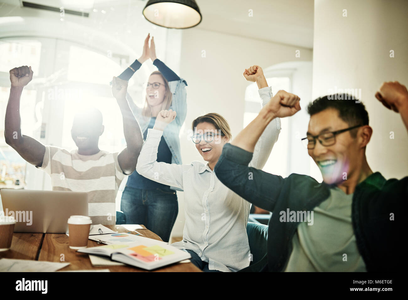Diverse group of ecstatic businesspeople cheering during a meeting ...