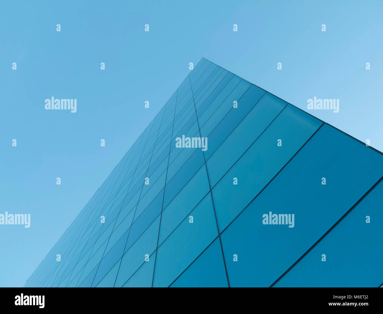 Corporate building. Low angle view of a diagonal glass facade, light ...