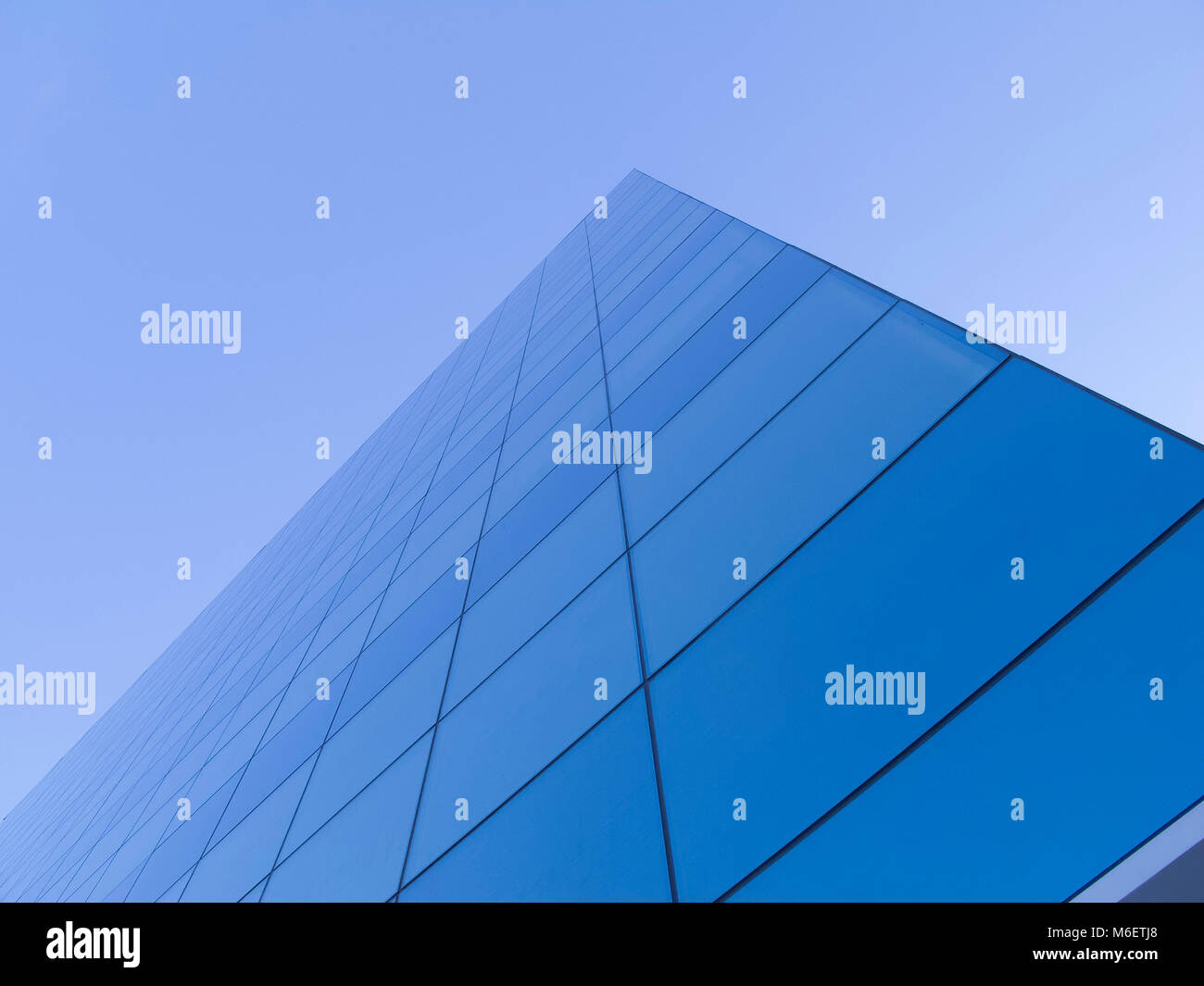 Corporate building. Low angle view of a diagonal glass facade, light ...