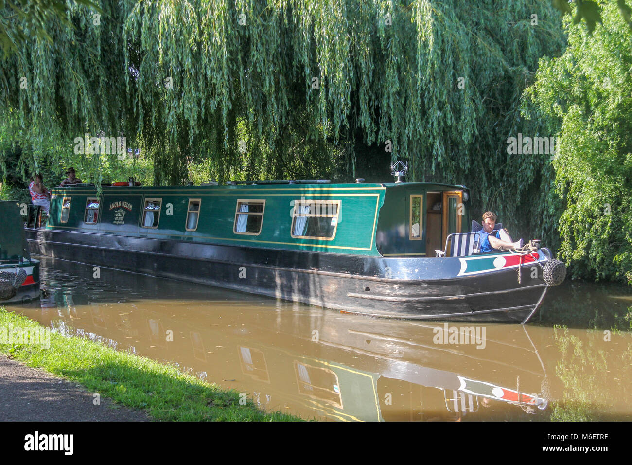 Man reading in the front of narrowboat, Shropshire Union canal ...