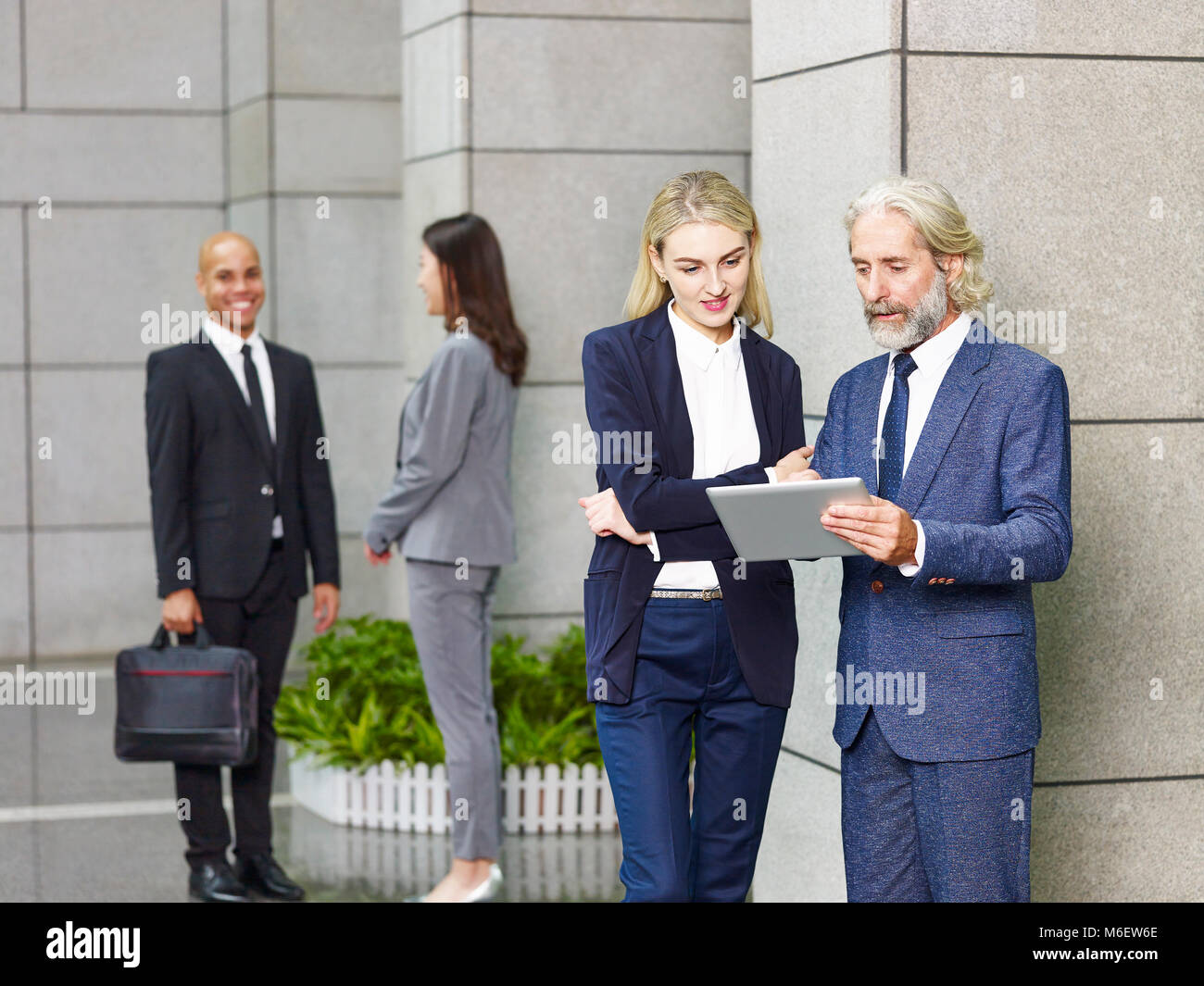 multinational corporate people standing talking in lobby of modern ...