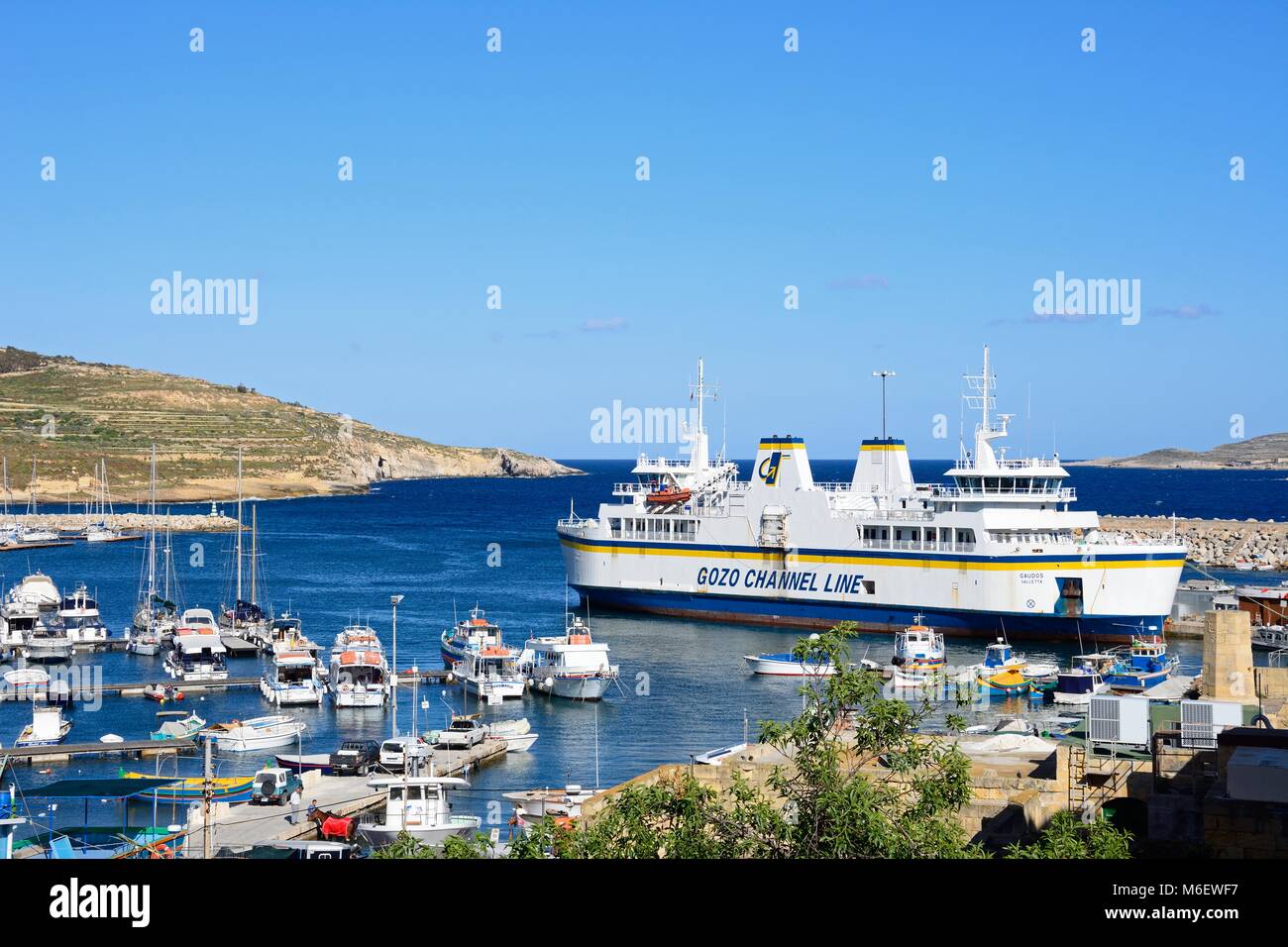 Fishing boats and yachts moored in the harbour with the Gozo ferry ...