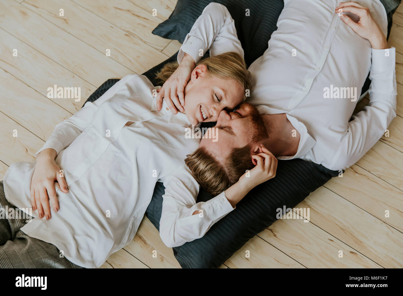 Loving couple lying and kissing on the floor at home Stock Photo - Alamy