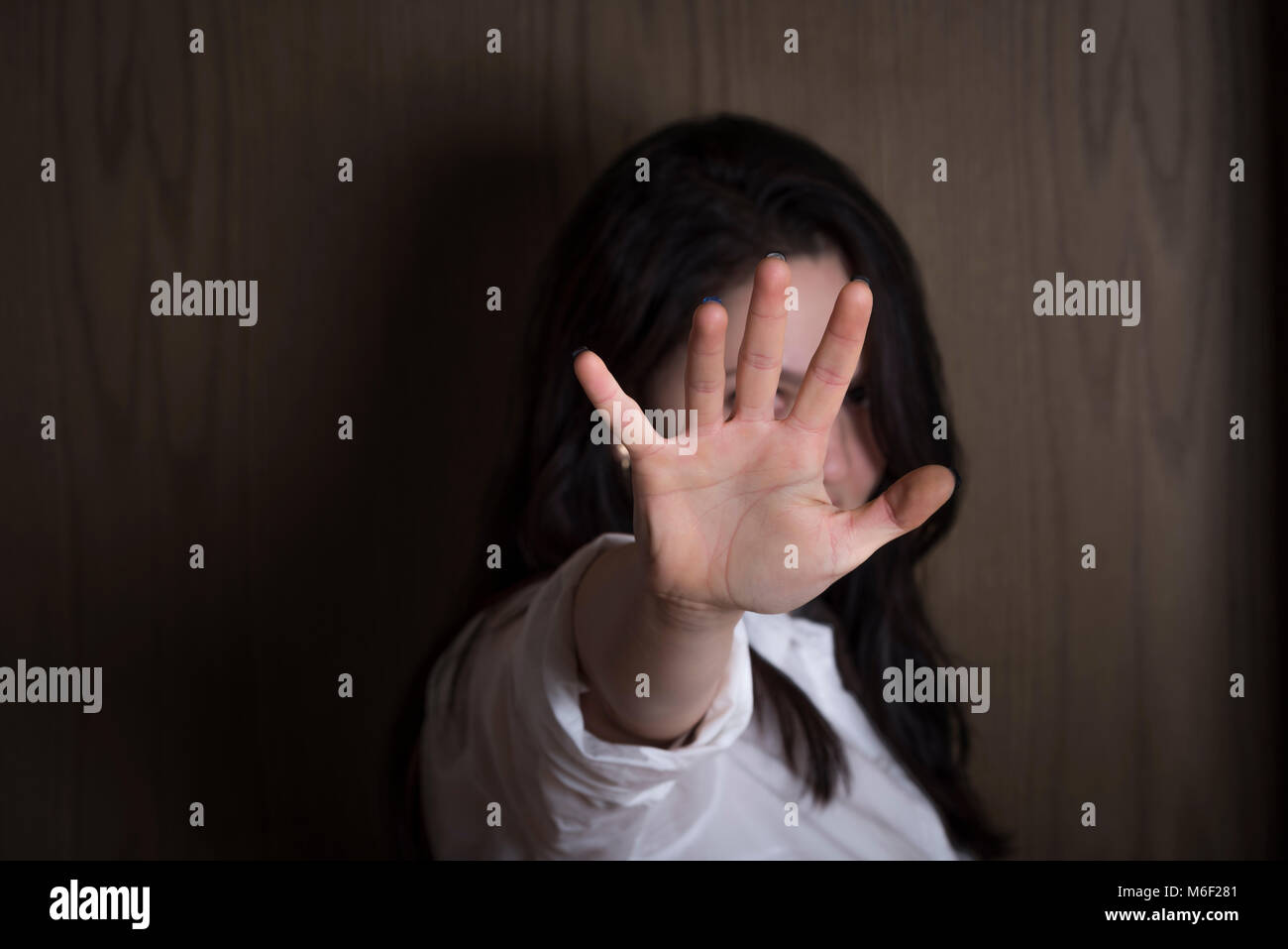 Brunette woman holding her hand stretched out toward the camera ...
