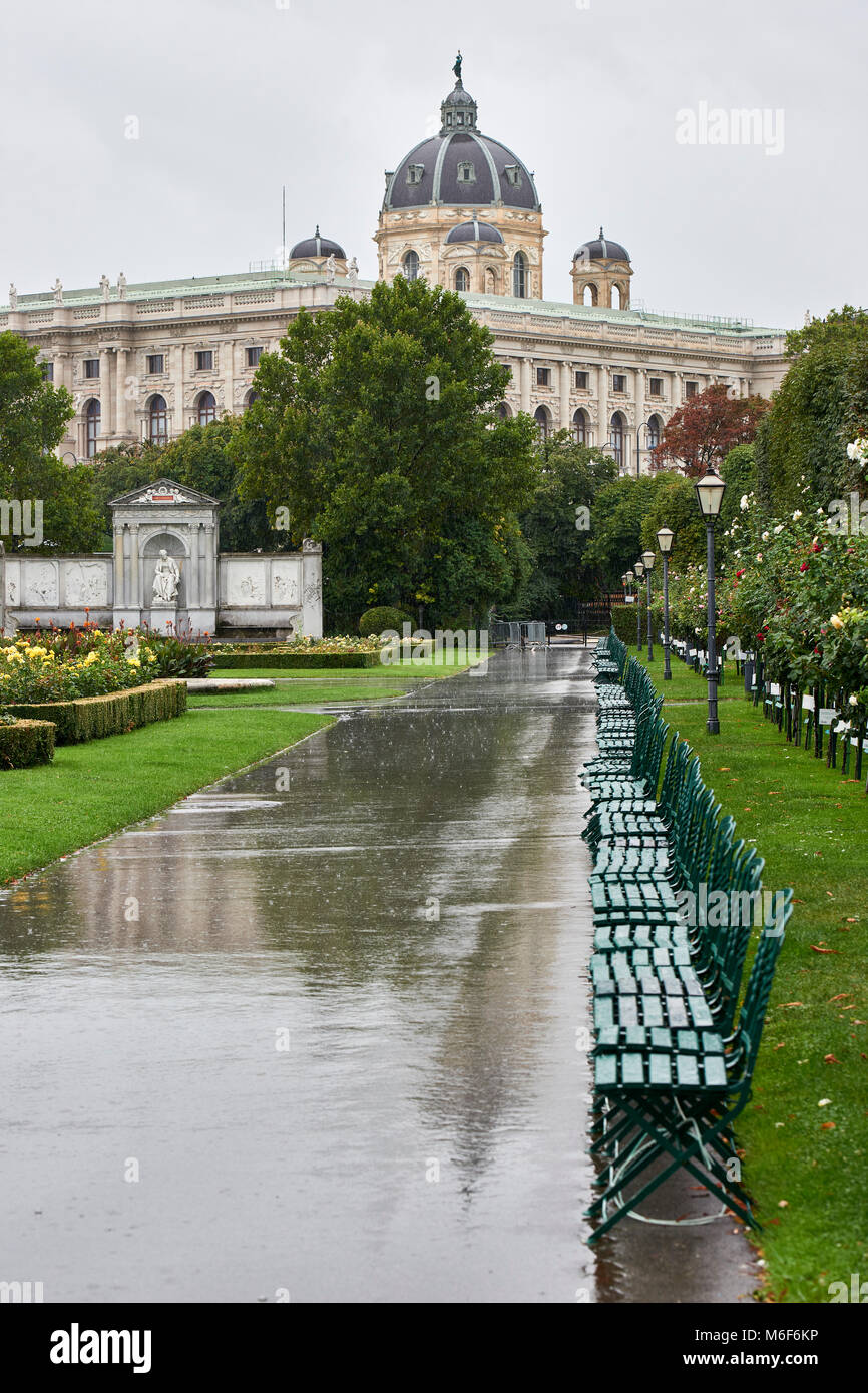 Row of empty benches in Volksgarten Vienna on a wet summer day, with ...