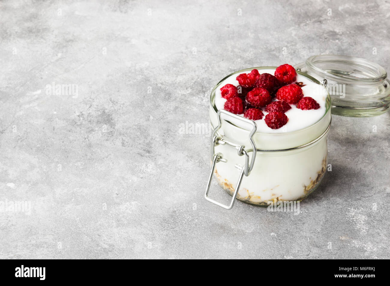 Glanola in glass jar with raspberry on a gray background. Copy space ...