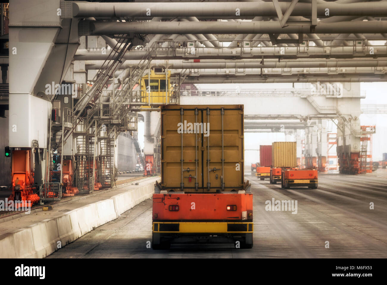 Automated vehicles moving shipping containers to and from gantry cranes in a port container ...
