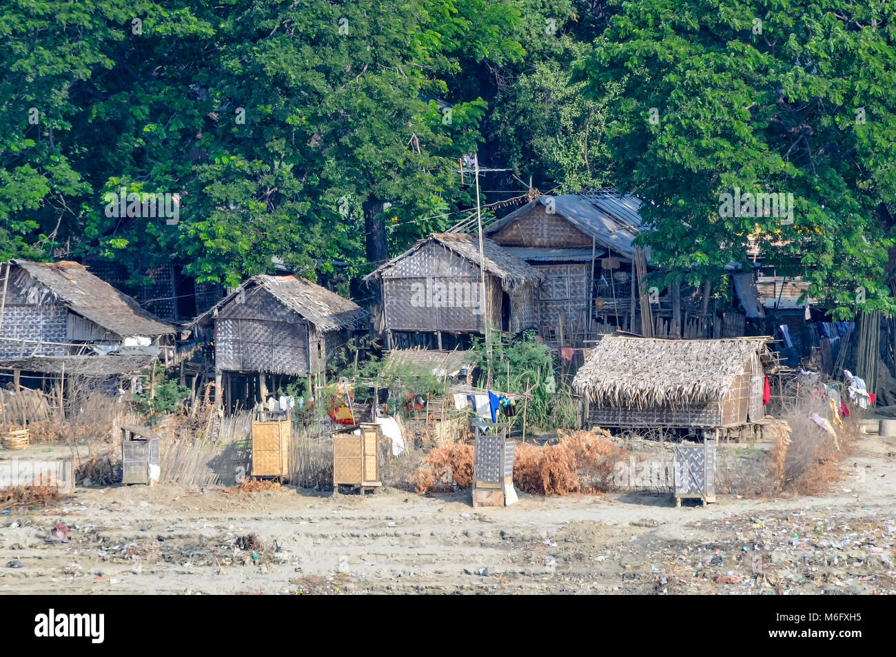 A view of a small village with huts on the riverbanks of the Irrawaddy ...