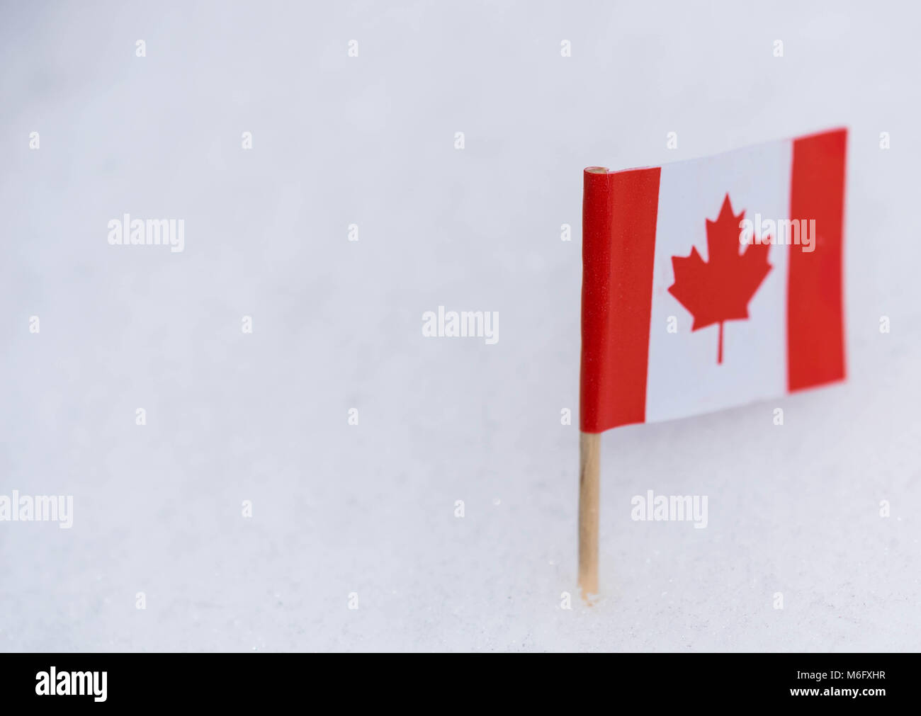 Canada flag made from paper with brown toothpick on white snow ...