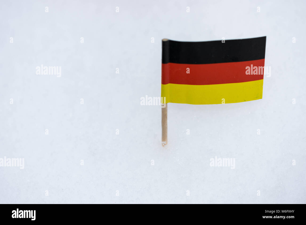 Small Germany flag made from paper with brown toothpick on white snow ...