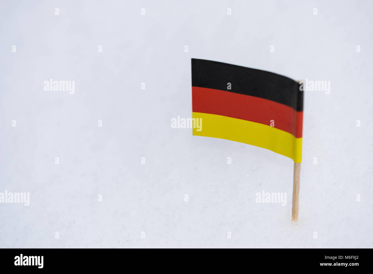 Small Germany flag made from paper with brown toothpick on white snow ...