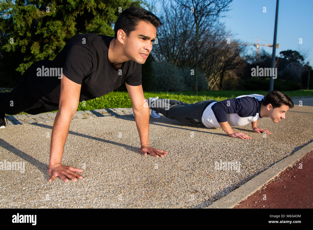 two young man making exercise, making push ups in a city garden Stock ...