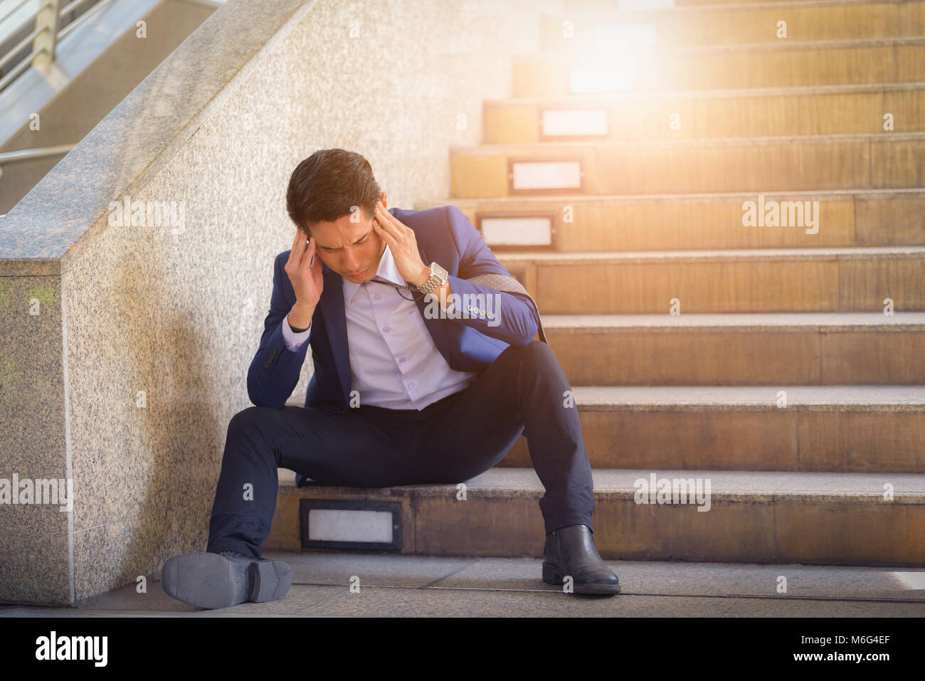 Sad businessman sitting on steps outside office Stock Photo - Alamy