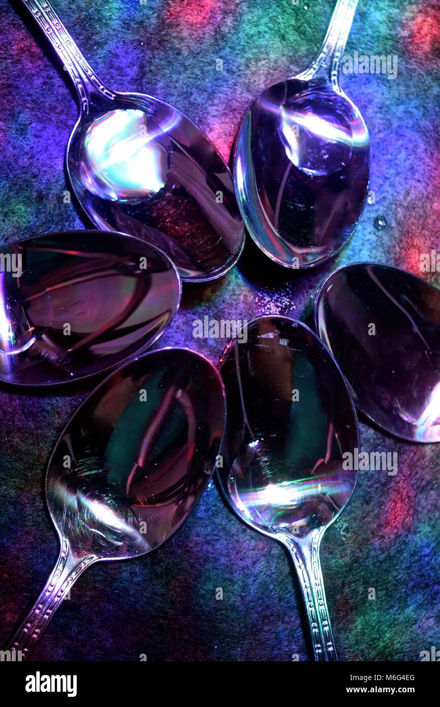 Spoons reflecting multicolored lights and taken in the dark closet ...