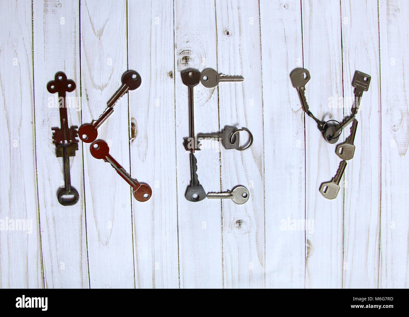 Old metallic different keys are laid out on a light background in the ...