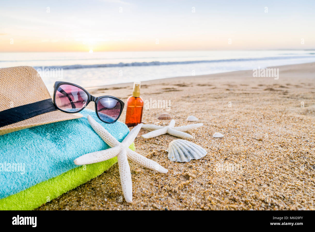 Summer accesories as sunglasses, towels, hat, sun block, shells and ...