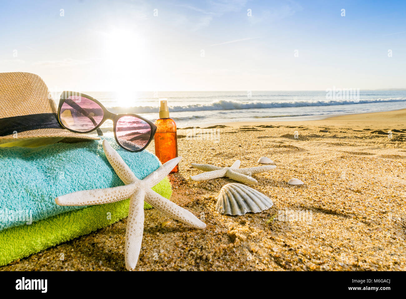 Summer accesories as sunglasses, towels, hat, sun block, shells and ...