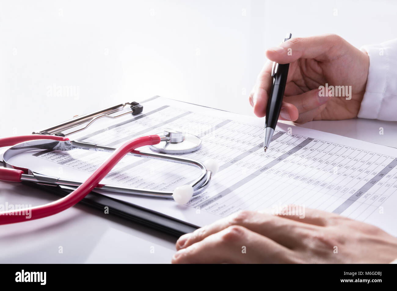 Close-up Of A Stethoscope Near Doctor's Hand Analyzing Report On ...