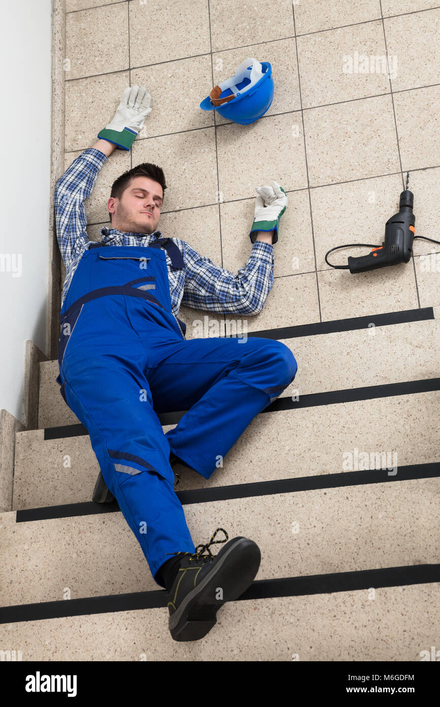 Unconscious Handyman Lying On Staircase With Helmet And Drill On Floor ...