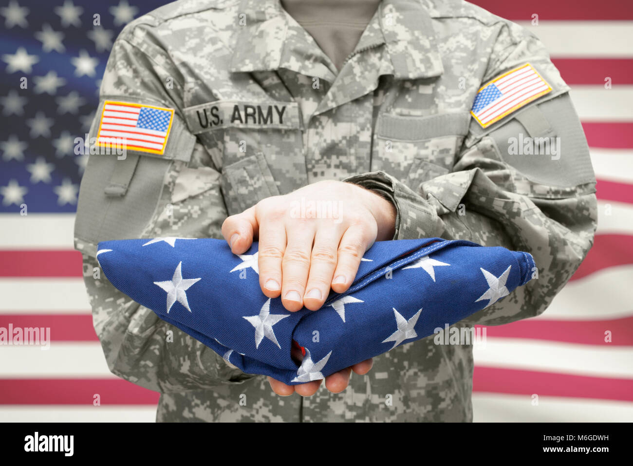 U.S. Army young soldier holding carefully folded USA flag before his ...