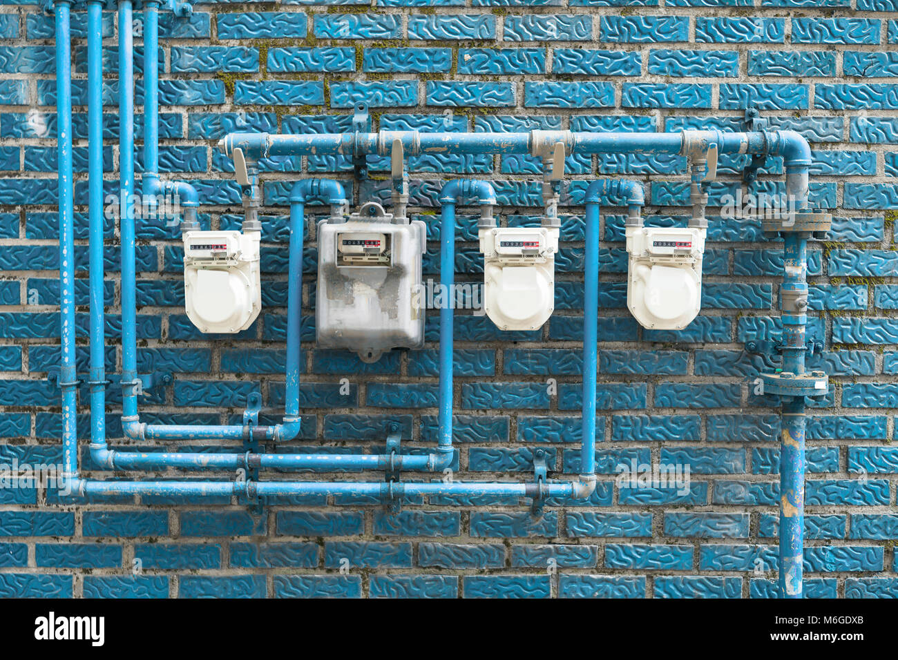 Row of natural gas meters with yellow pipes on building brick wall ...