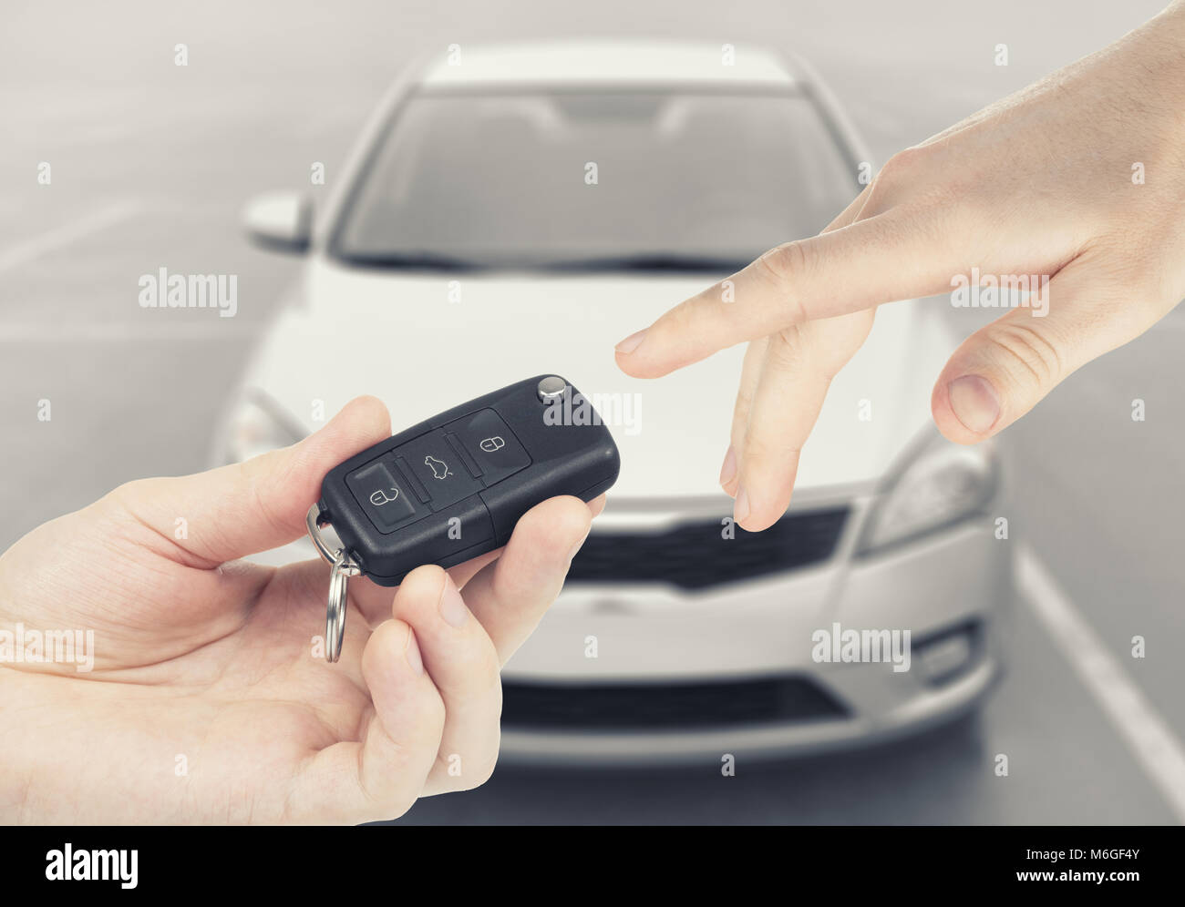 One person passing car-keys to another person with car on background ...