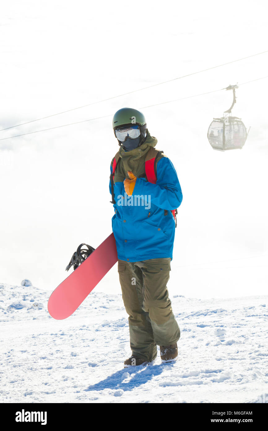 Winter sports concept - young male snowboarder carrying his snowboard ...