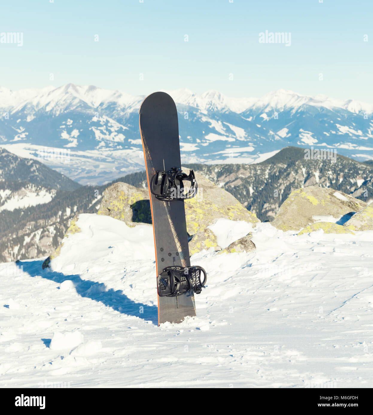 Male snowboarder holding his snowboard at the top of a mountain ...