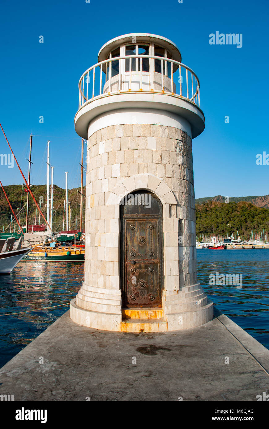 Small lighthouse on a concrete pier against the background of yachts ...