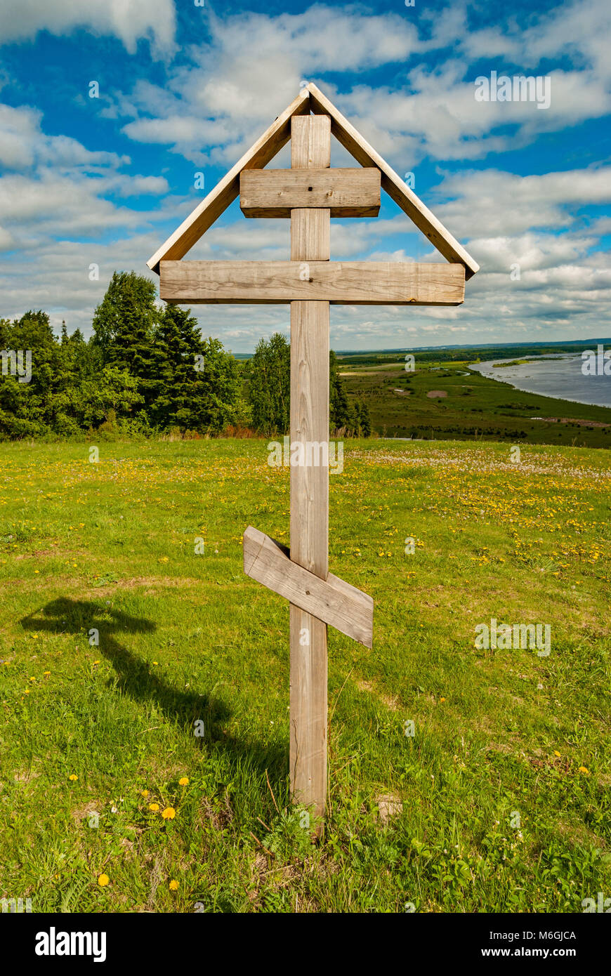 Wooden Orthodox cross stands on a hill with a river background ...