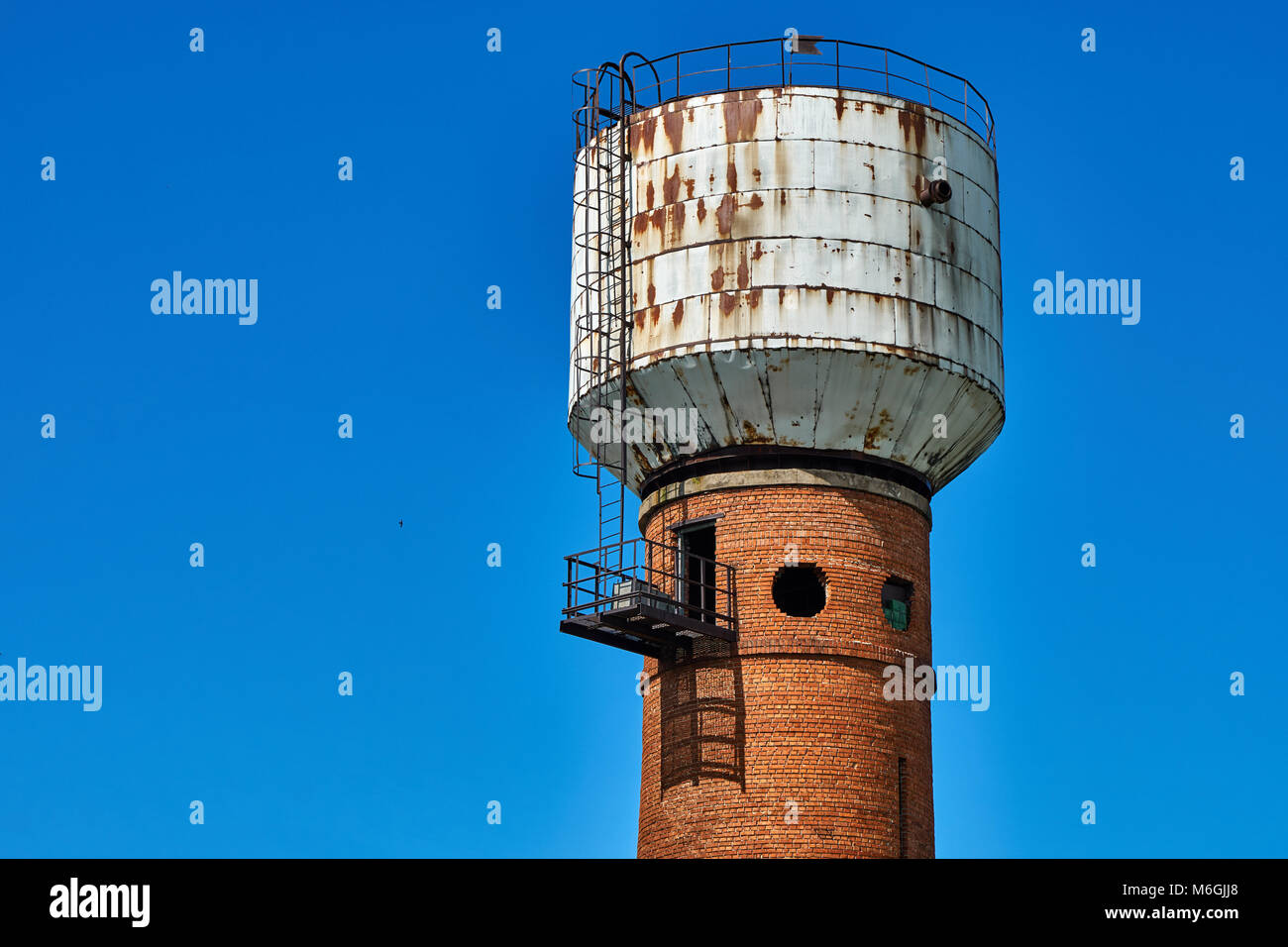 High water-pressure tower made of brick and metal with round windows ...