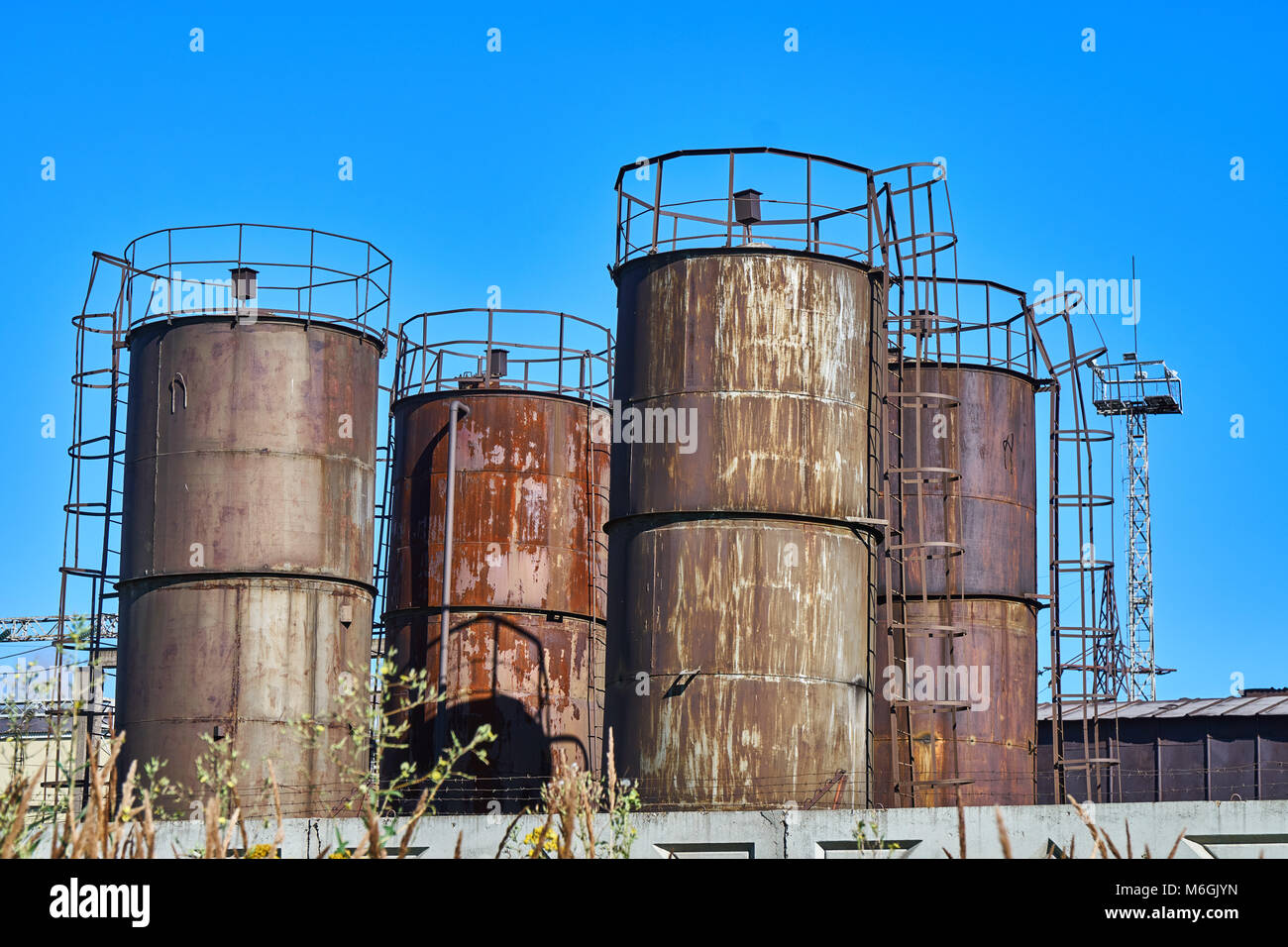 Old rusty industrial fuel storage tanks against blue sky Stock Photo ...