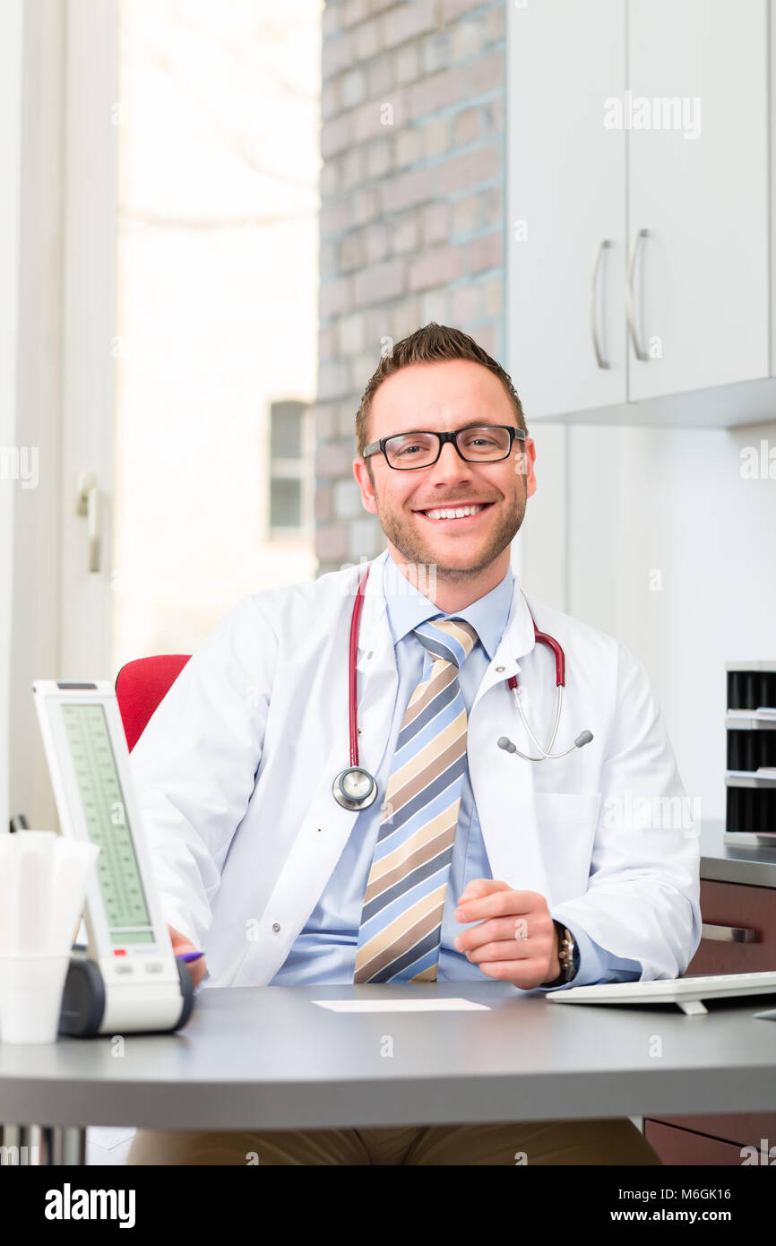 Young doctor sitting in surgery at desk Stock Photo - Alamy