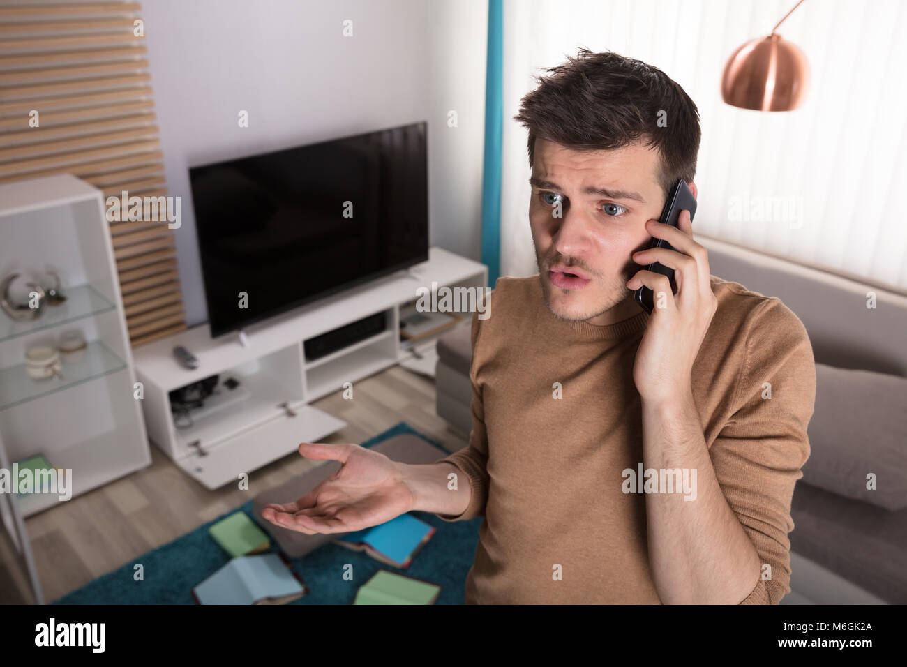 Worried Young Man Talking On Phone About House Robbery Stock Photo - Alamy
