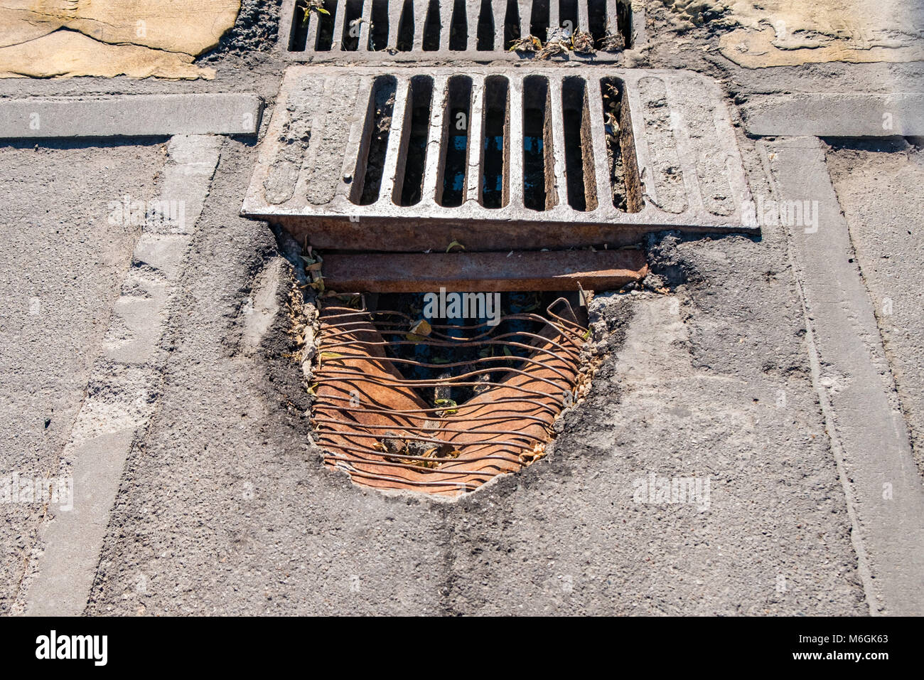 Storm drain embedded in cracked asphalt, showing signs of water damage ...