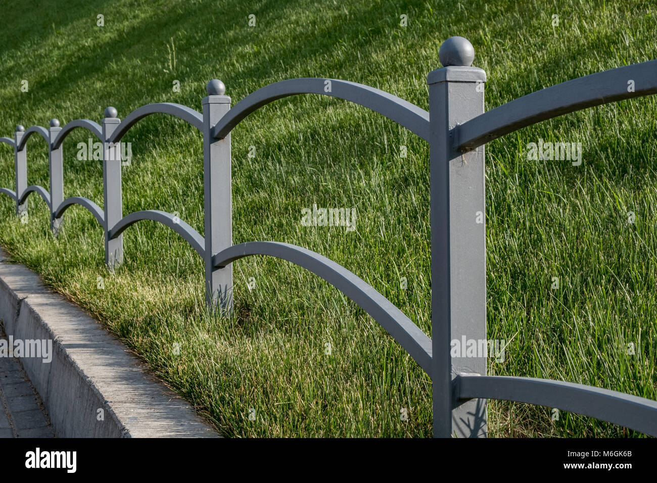 Metal low fence against the background of green grass Stock Photo - Alamy