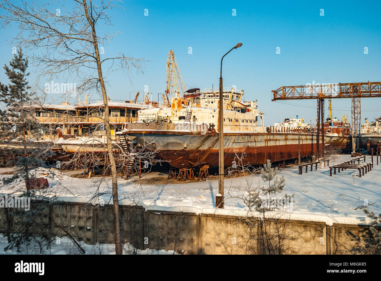 Old rusty ferries located near snowy shore of harbor against cloudless ...
