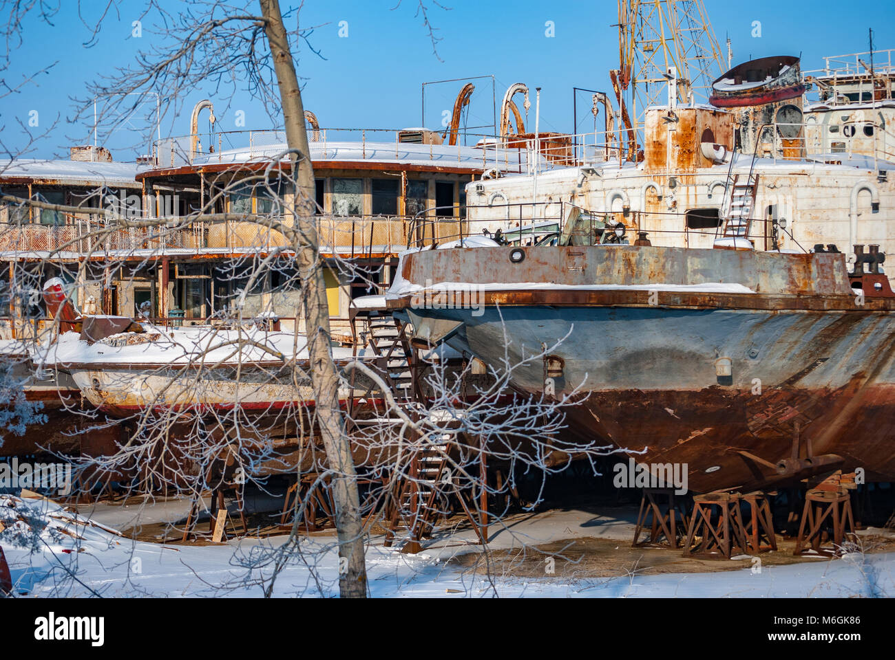 Old rusty ferries located near snowy shore of harbor against cloudless ...