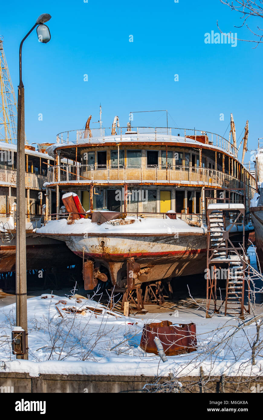 Old rusty ferries located near snowy shore of harbor against cloudless ...